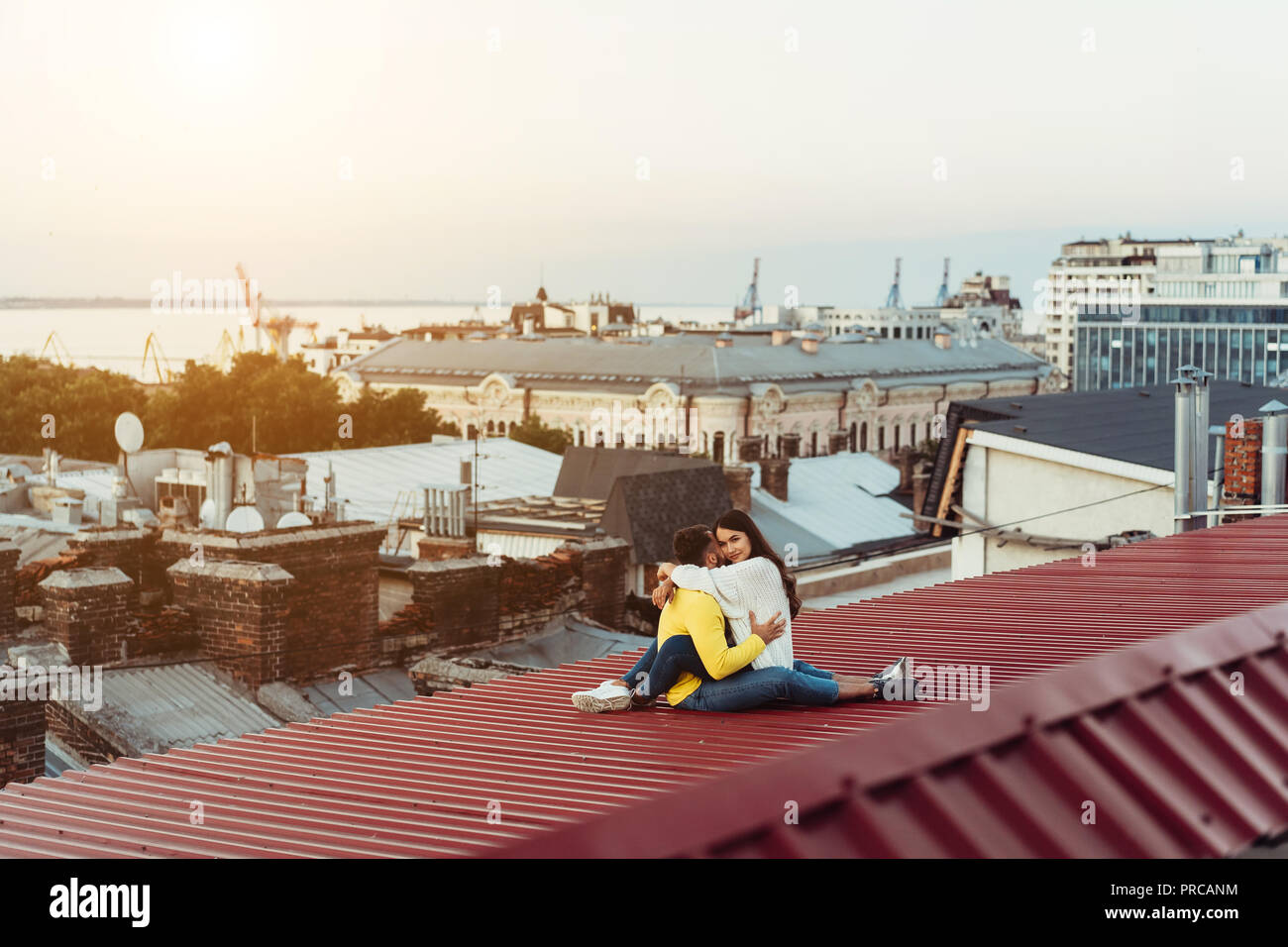 Loving young couple is sitting on the roof of the house Stock Photo - Alamy