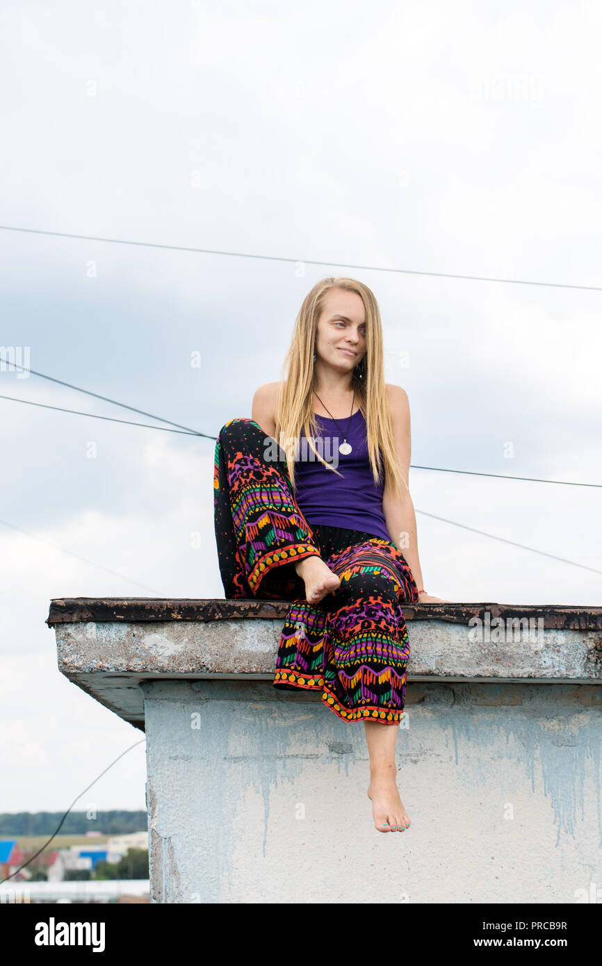 girl is sitting on the roof against a cloudy sky background Stock Photo ...