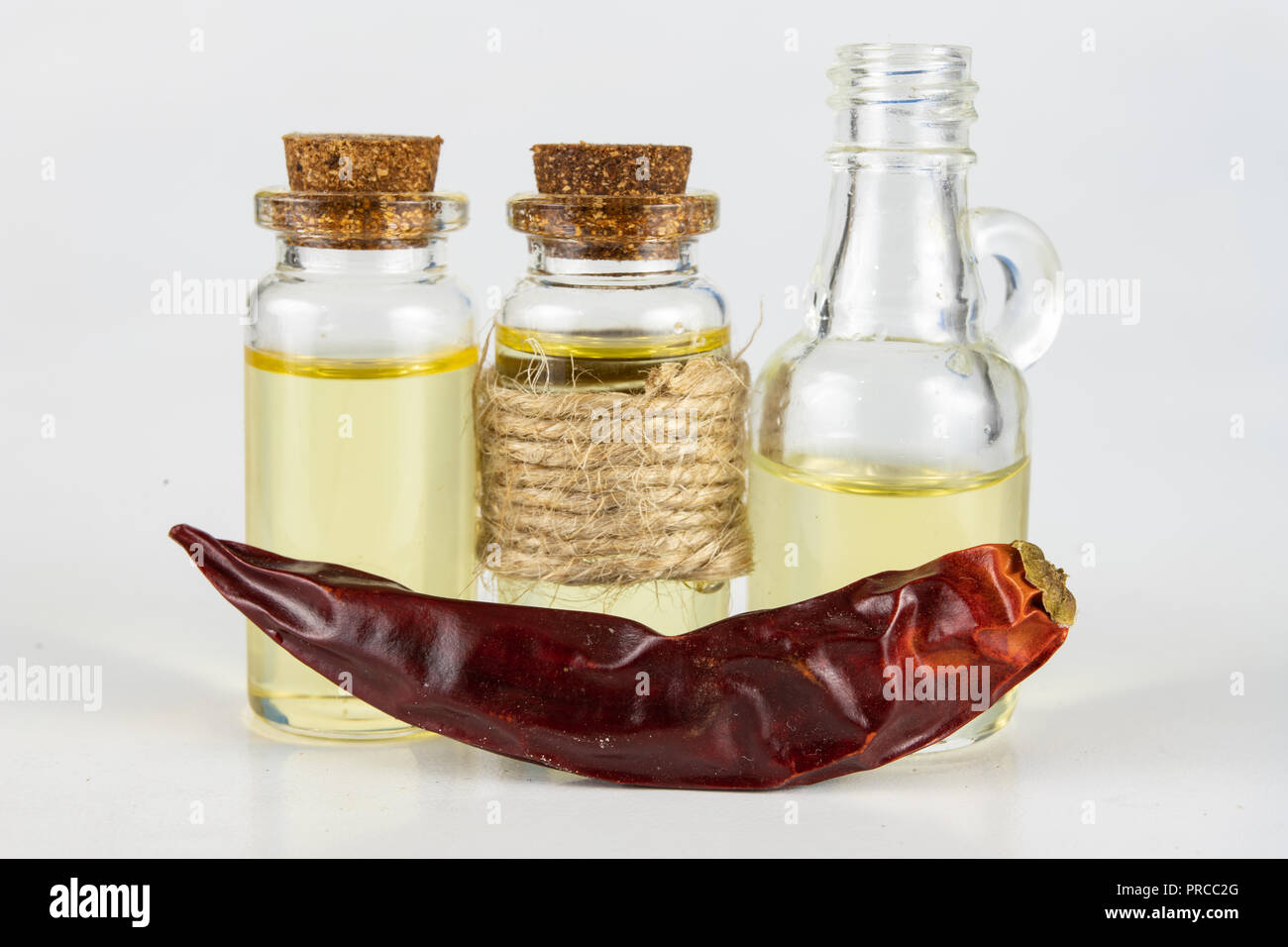 Dried peppers and a vial of oil on a white kitchen table. Spices ...