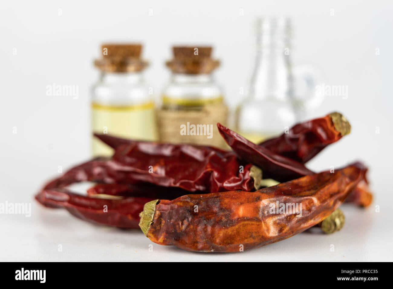 Dried peppers and a vial of oil on a white kitchen table. Spices ...