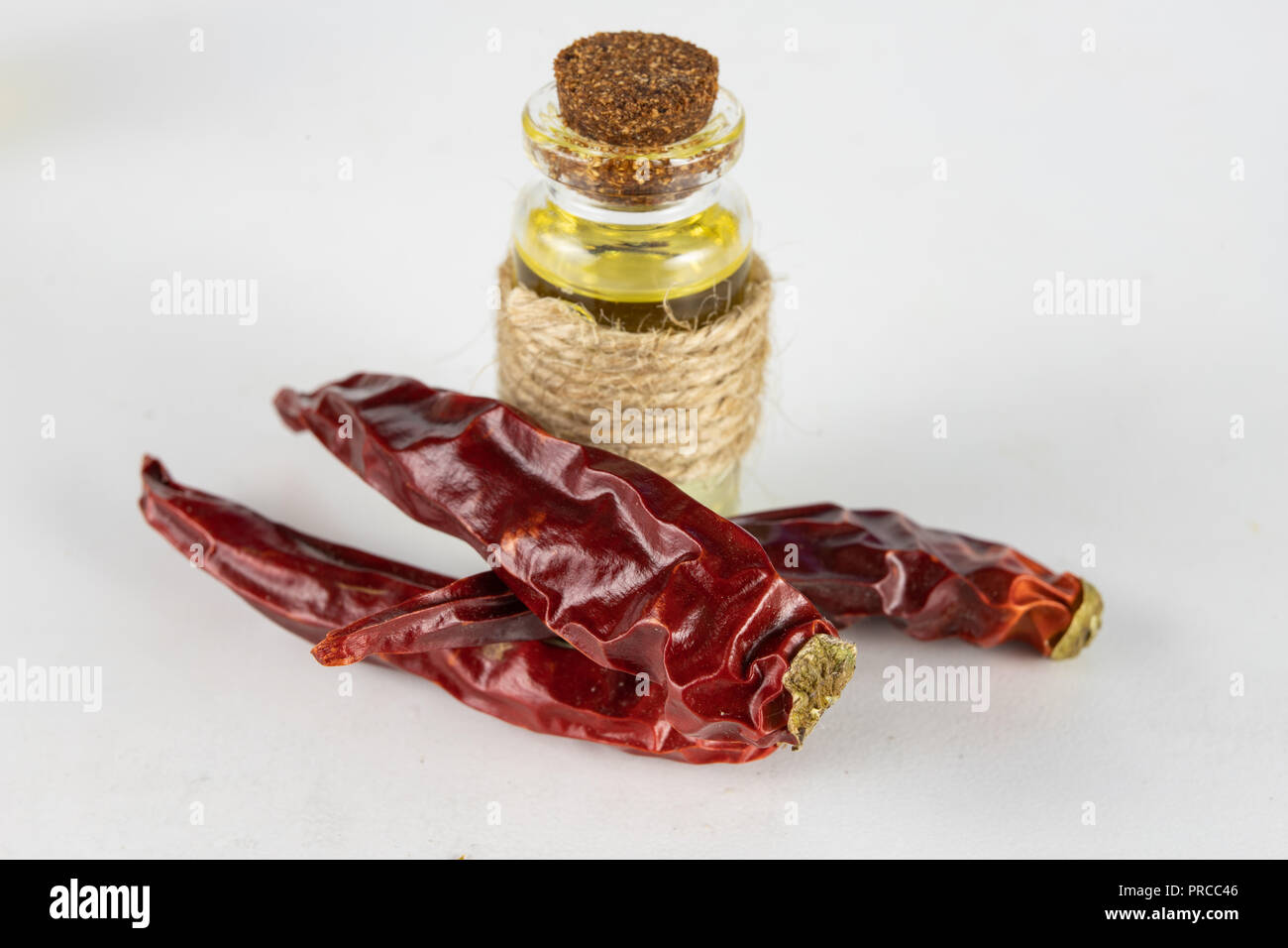 Dried peppers and a vial of oil on a white kitchen table. Spices ...