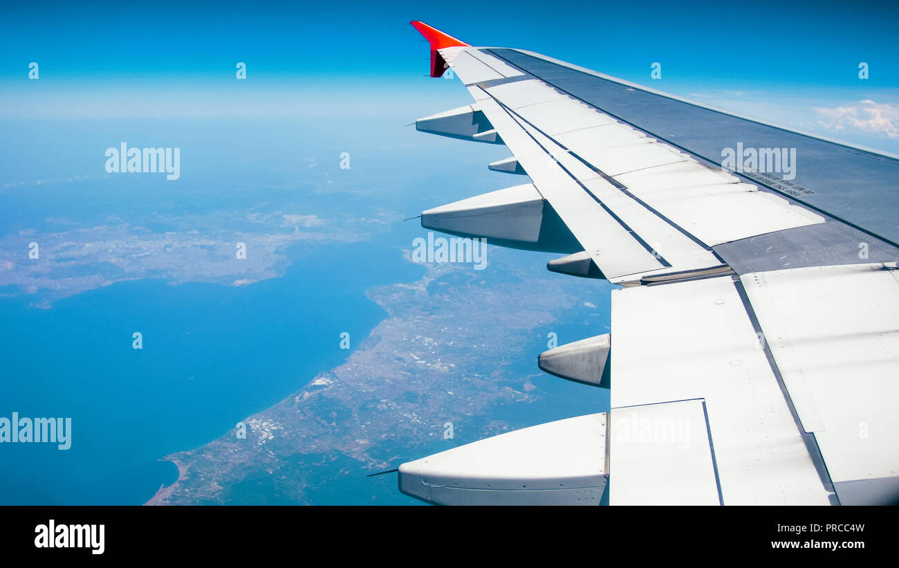 View from window of airplane wing above sea and land on bright sunny ...