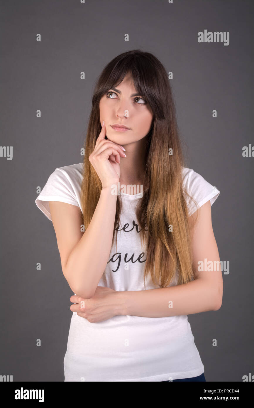 Young woman is thinking about something. Female in a white T-shirt on a ...