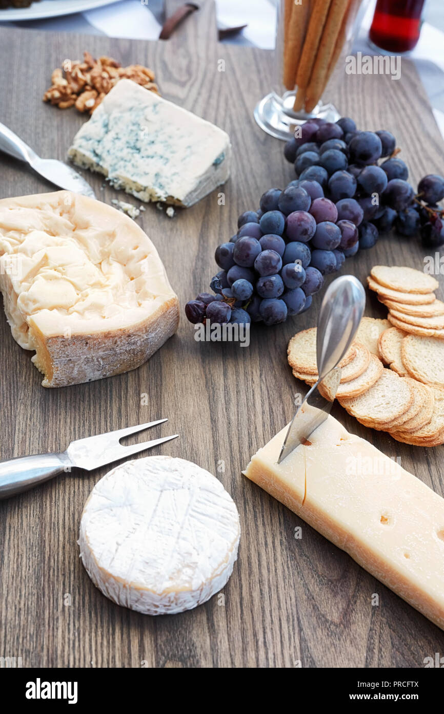 Various types of luxury cheese on wooden cheese platter under natural ...