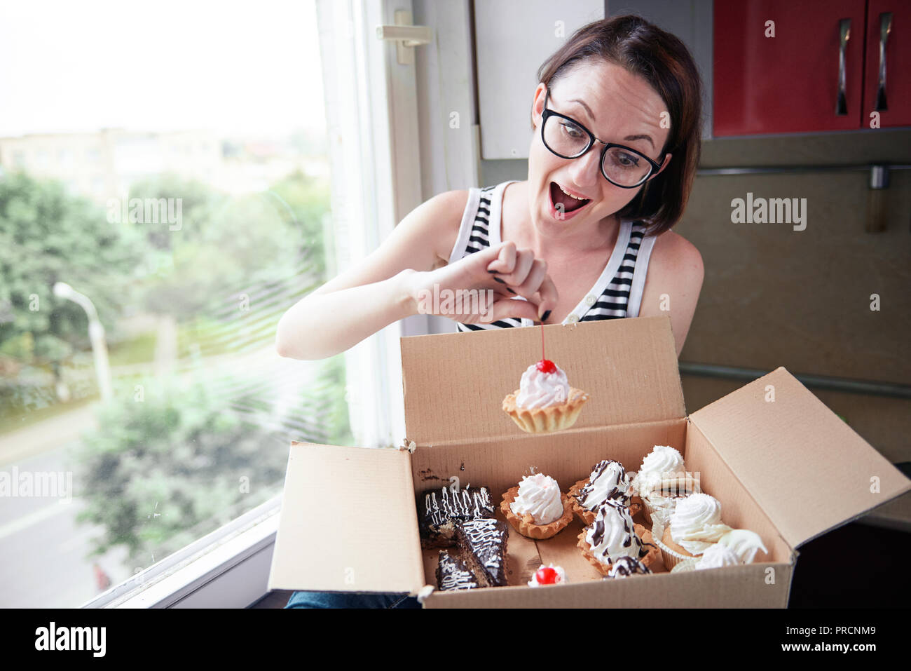 girl eating tasty cakes, sitting by the window, sweet food and pleasure ...