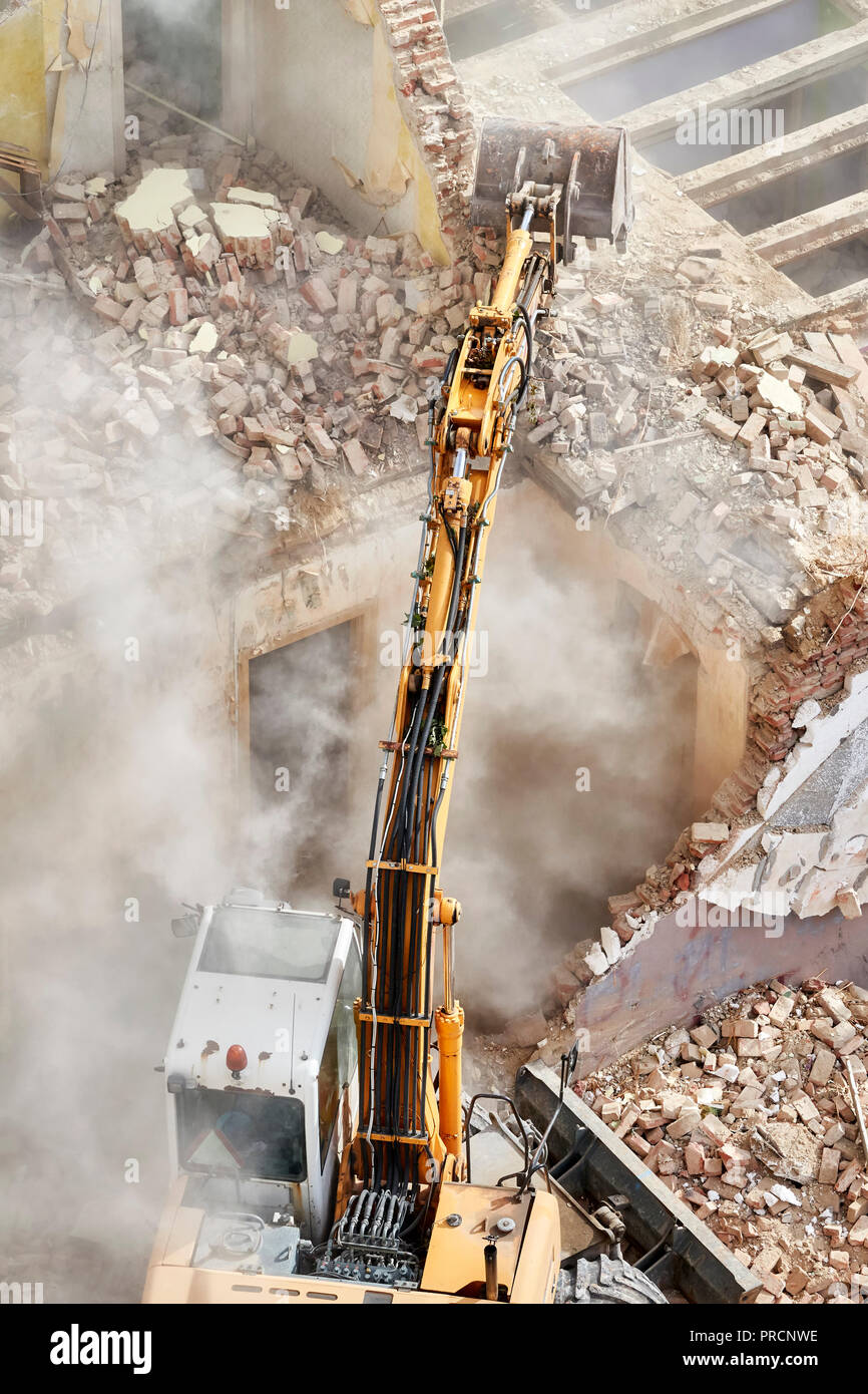Building demolition with an excavator in dust cloud, view from above ...
