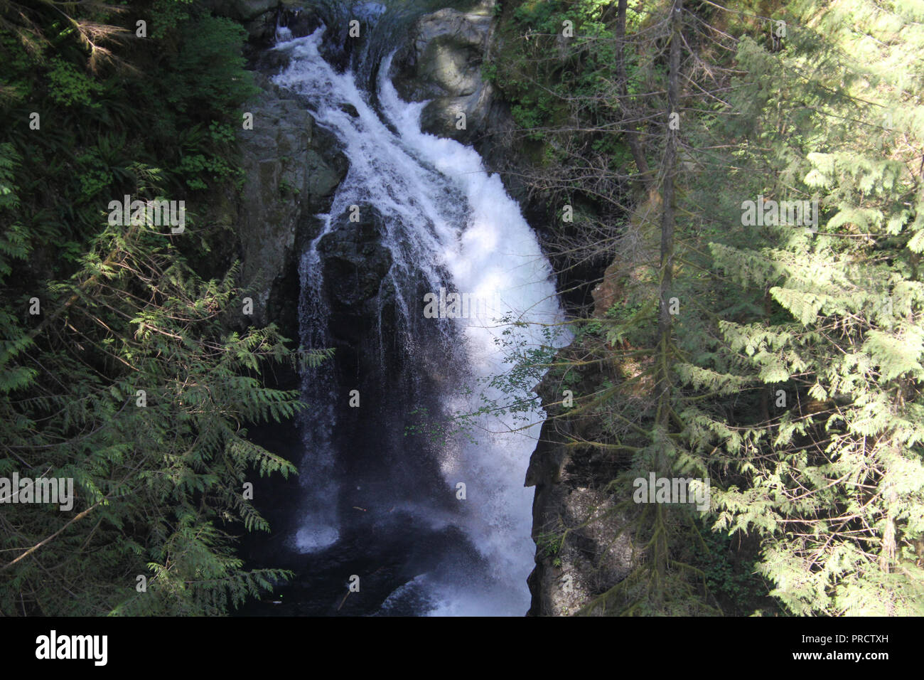 A waterfall falling down a rock wall in the middle of a stream with ...