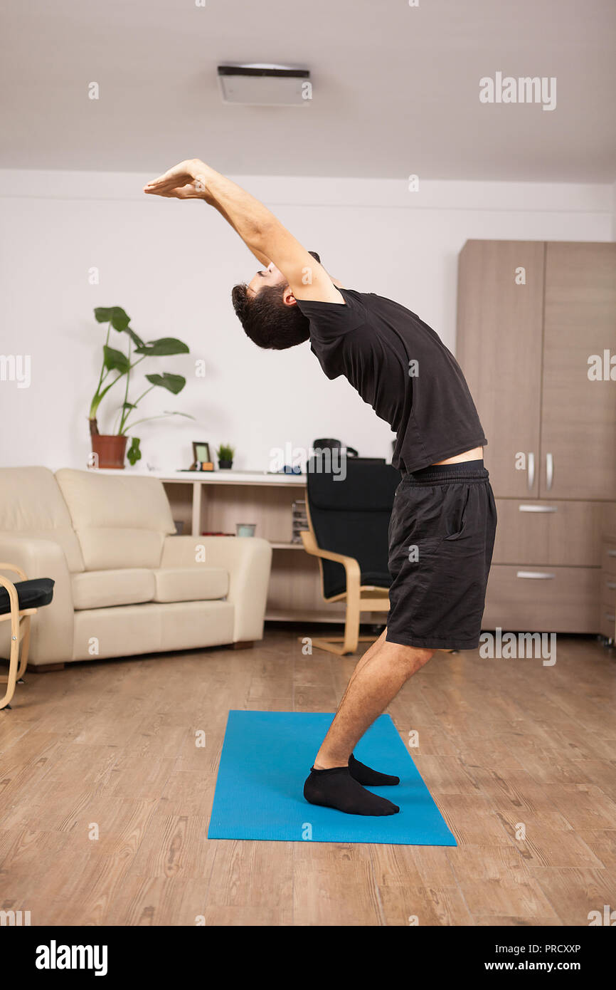 Attractive man with beard doing back stretch standing up. Adult working ...