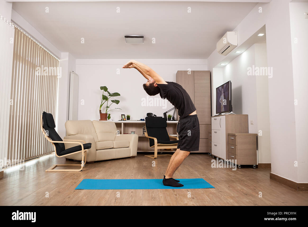 Attractive man with beard doing back stretch standing up. Adult working ...