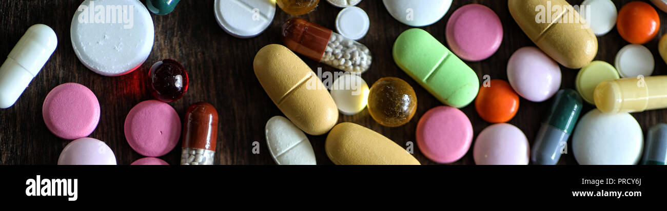 Medical background of various colorful medications on a textured wooden ...