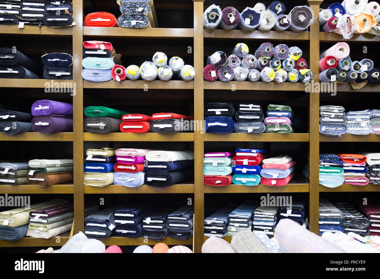 Variety of different fabric bolts exposed on shelves of fabric shop ...