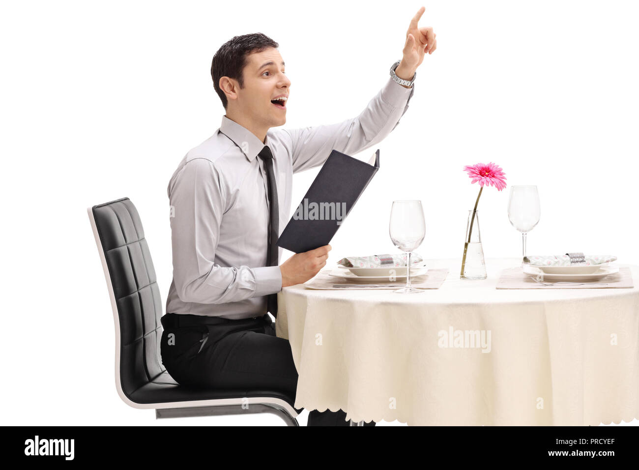 Young man seated at a restaurant table calling the waiter isolated on ...