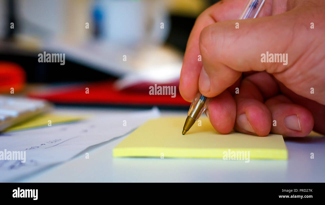 Male hand writing with a pen on a yellow sheet Stock Photo - Alamy