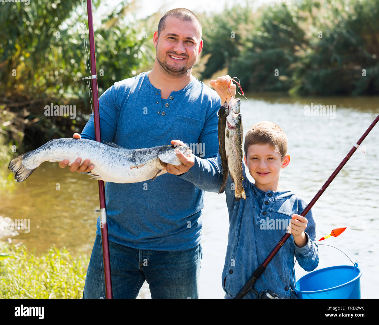 happy father and teenager son showing catched fish in wild river Stock ...