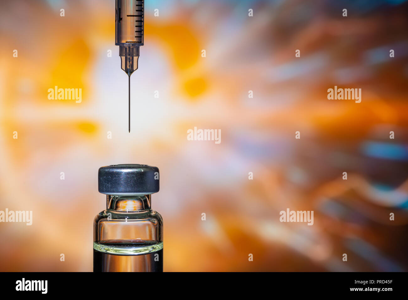 A syringe with the needle point to the vaccine vial on the colorful ...