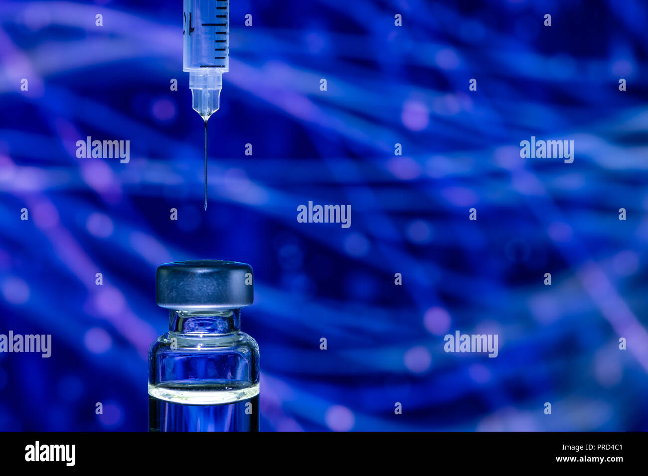 A syringe with the needle point to the vaccine vial on the colorful ...