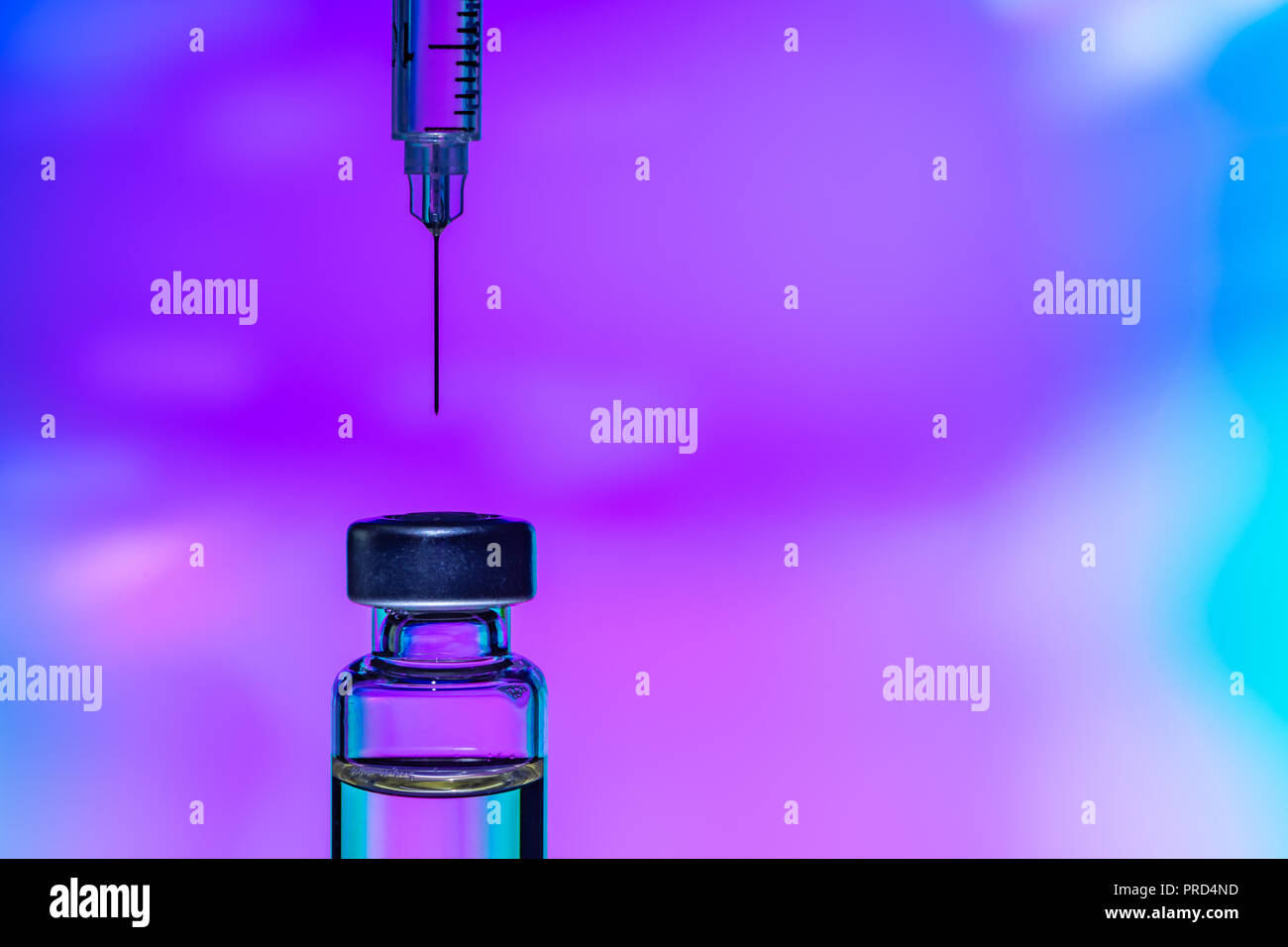 A syringe with the needle point to the vaccine vial on the colorful ...