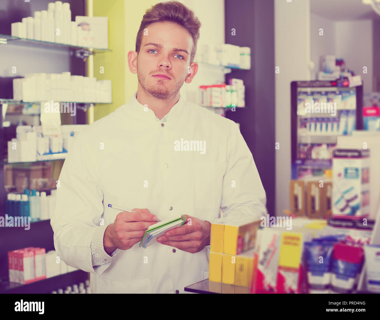 Adult pharmacist wearing uniform and working in pharmaceutical shop ...