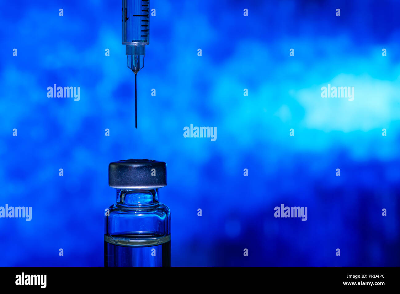 A syringe with the needle point to the vaccine vial on the colorful ...