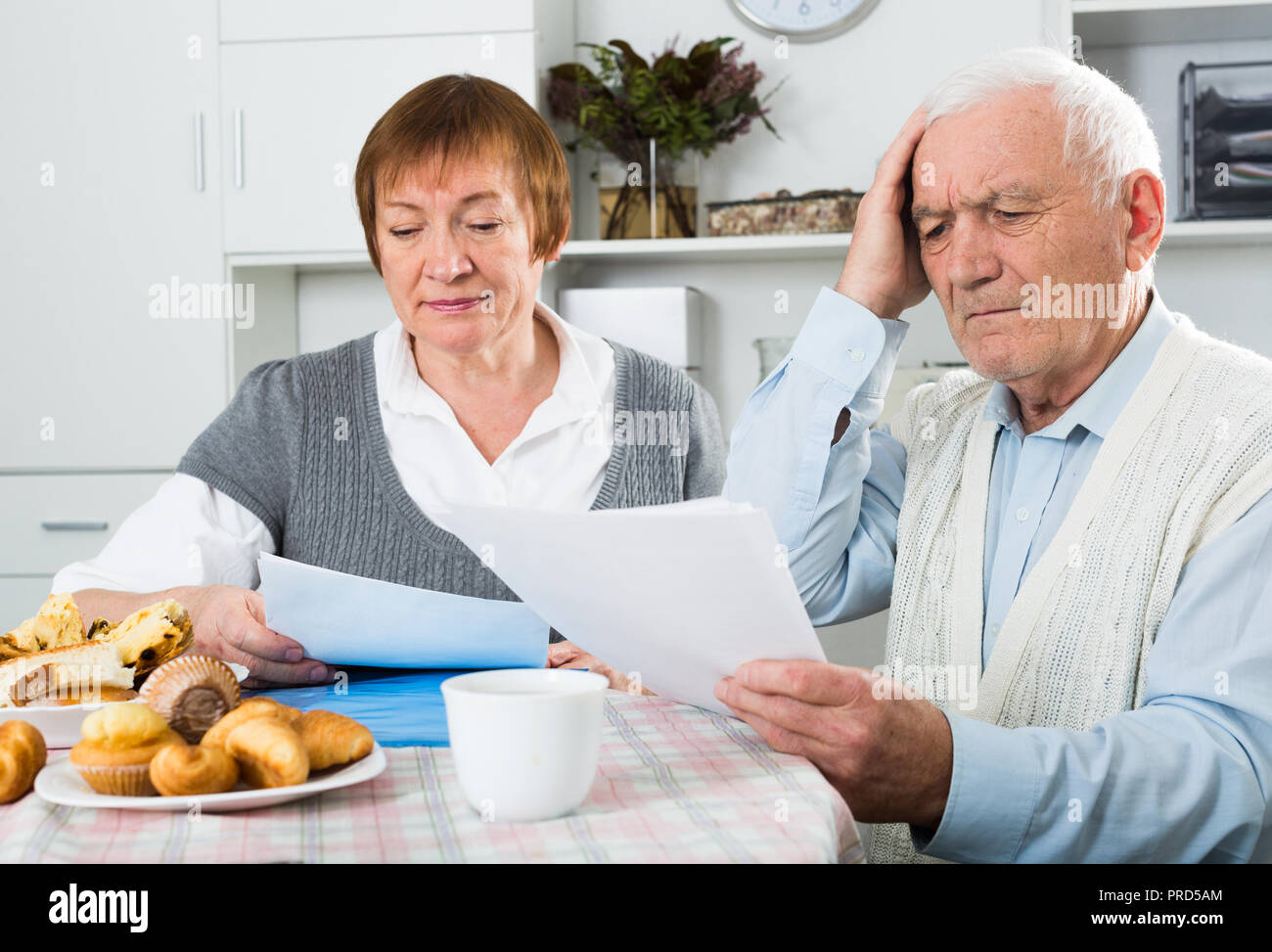 Elderly husband and wife carefully study contract before signing at ...