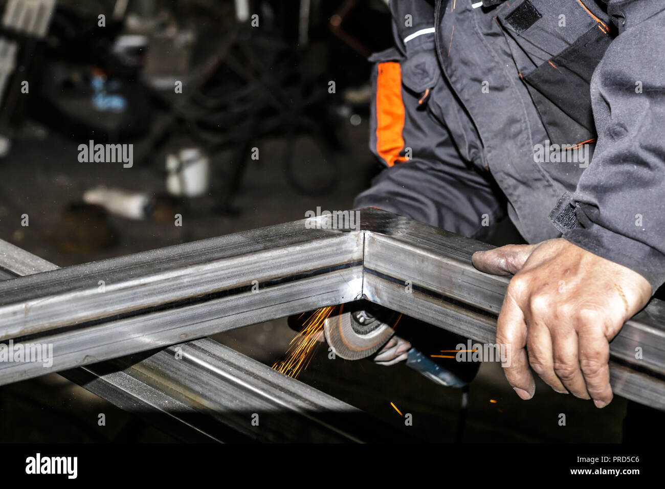 Craftsman sawing metal with disk grinder in workshop. Grinding metal ...