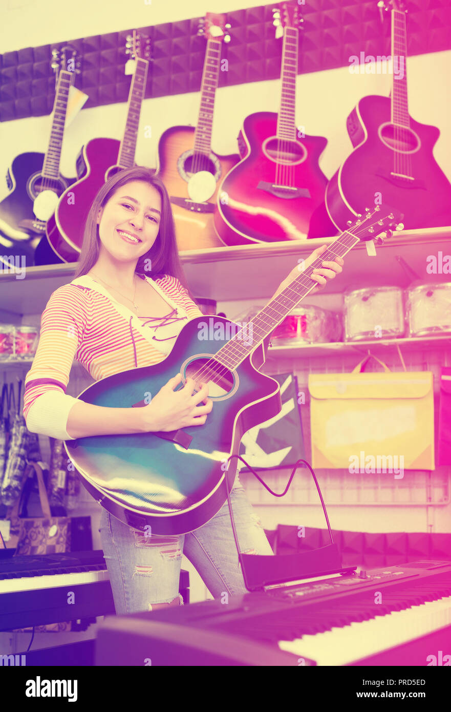Happy young customer buying new guitar in store and smiling Stock Photo ...