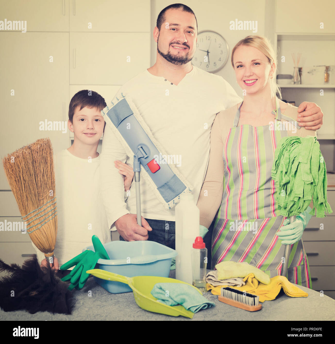 Portrait of friendly smiling family standing at room ready to clean ...