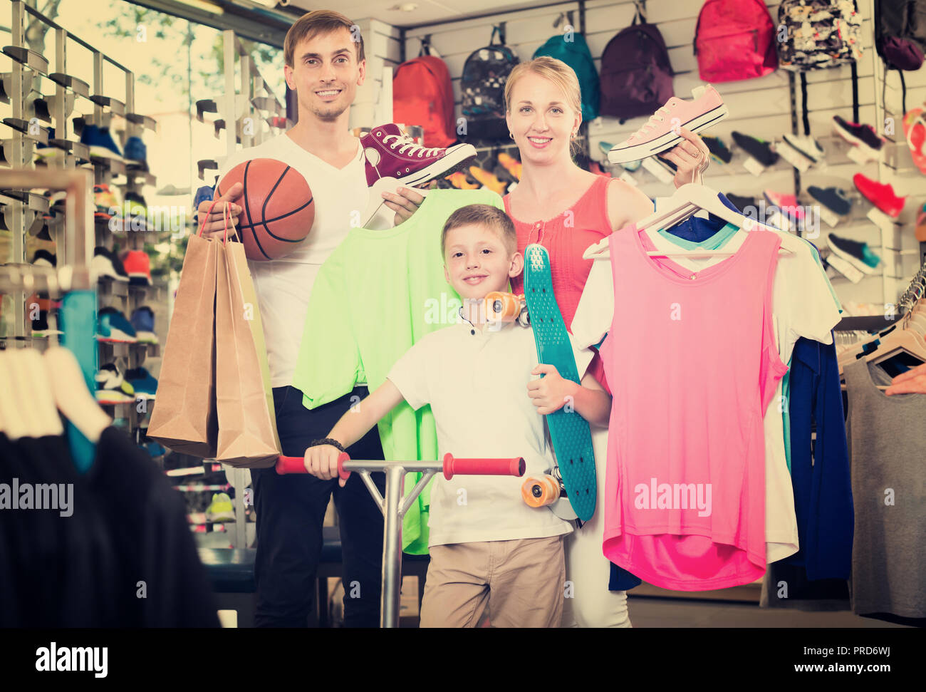 Adult parents with boy in school age shopping clothing in sport store ...