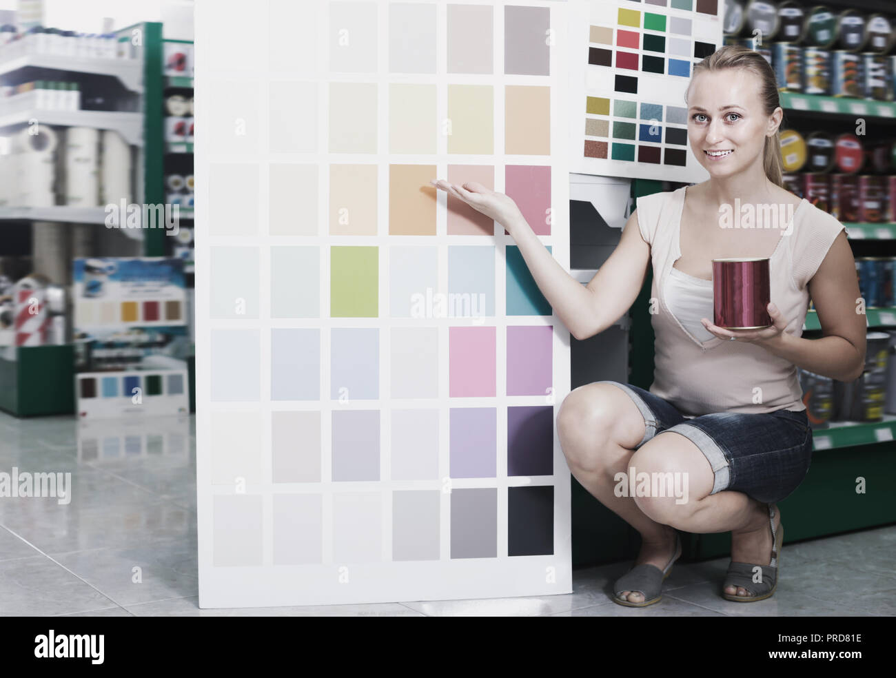 Cheerful adult woman picking color for paint looking at palette in ...