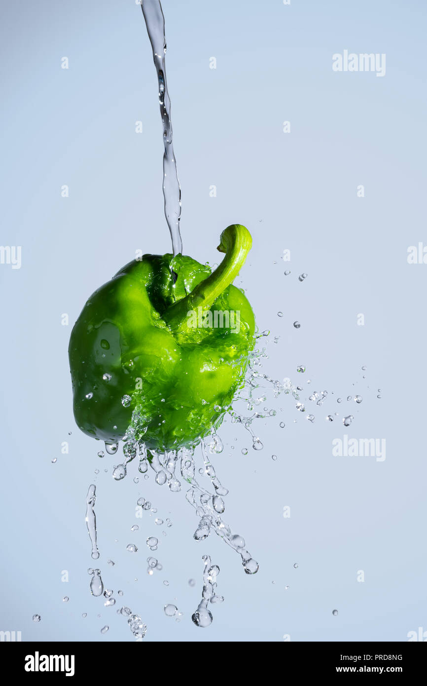Pouring the water on top of green bell pepper with the water splash in ...