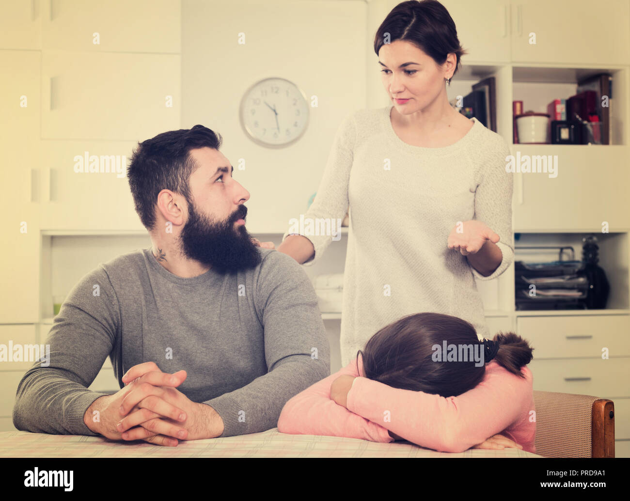 Young mother correcting her husband and child for disobedience at home ...