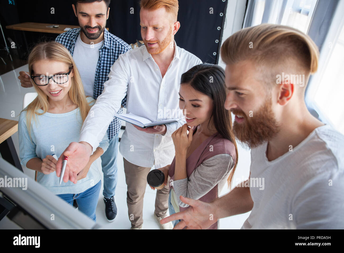 Group of young colleagues dressed casual standing together in modern ...