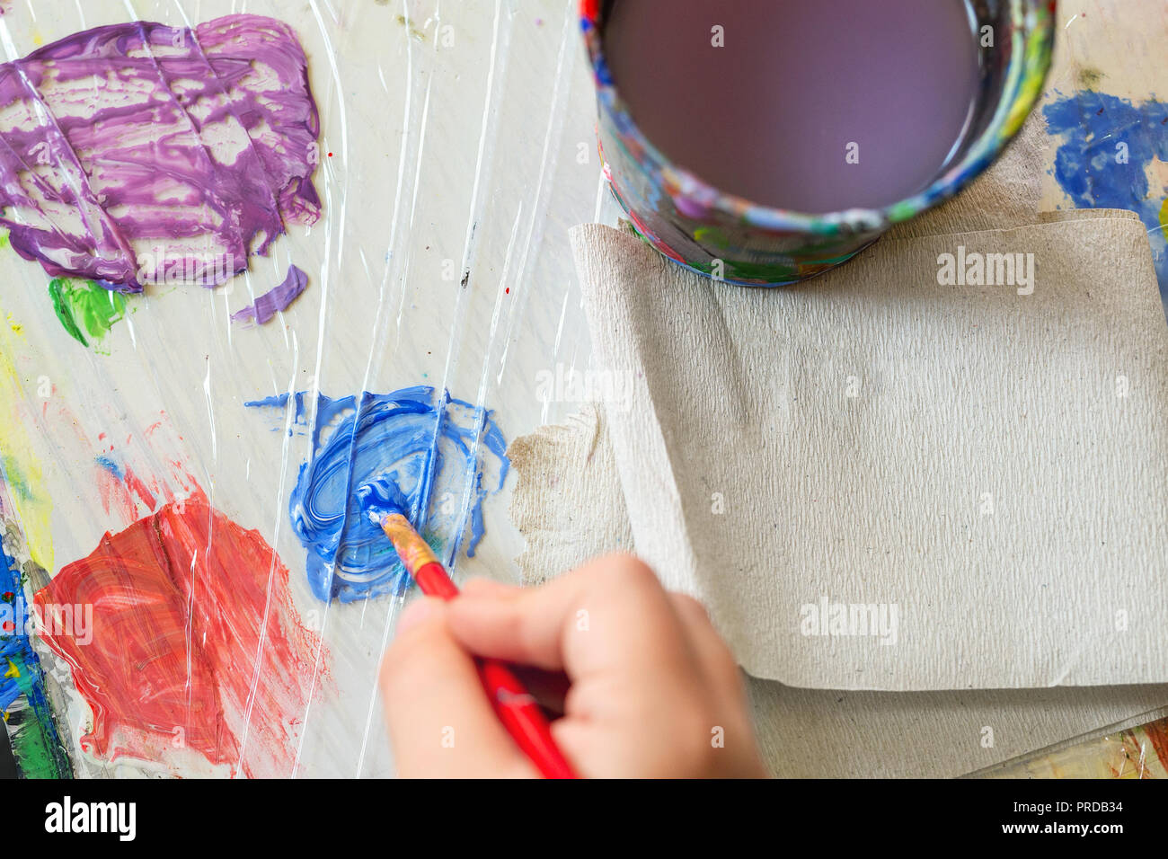 Top view of color palette and artist hand mixing paints with brush ...
