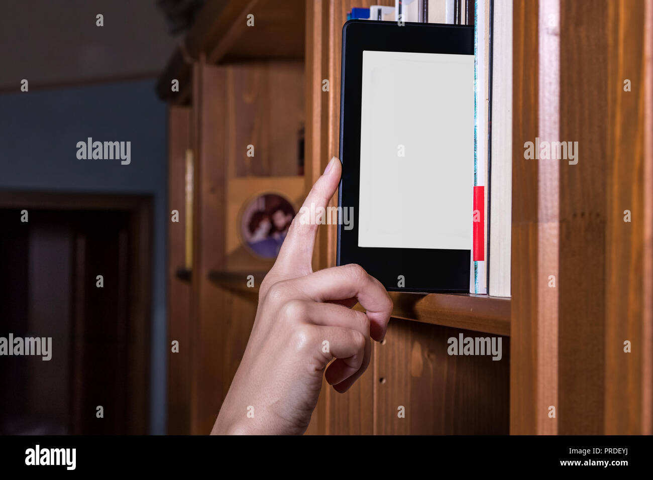E reader on bookshelf, woman hand Stock Photo - Alamy