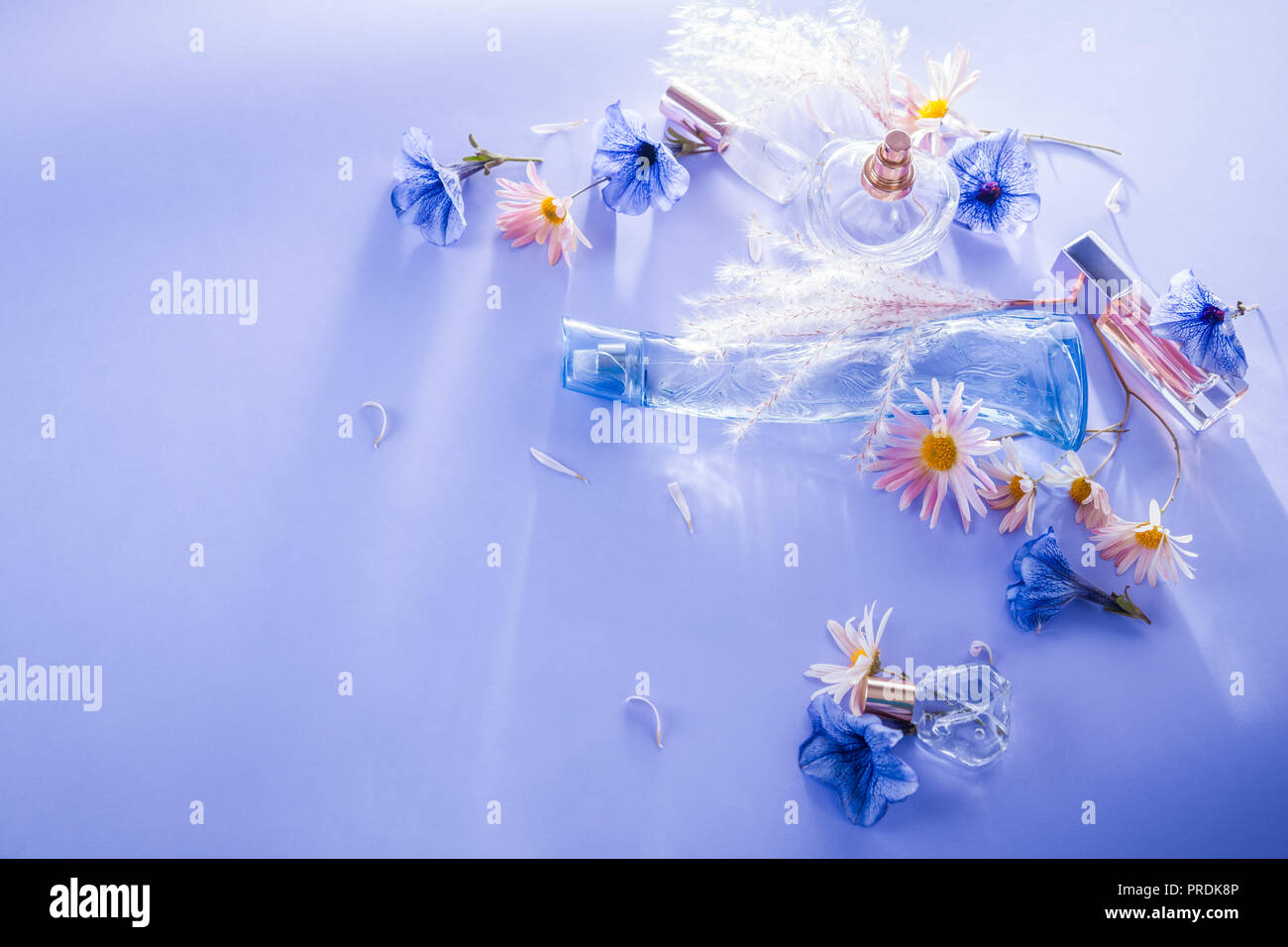Bottles of perfume with flowers on blue background Stock Photo - Alamy