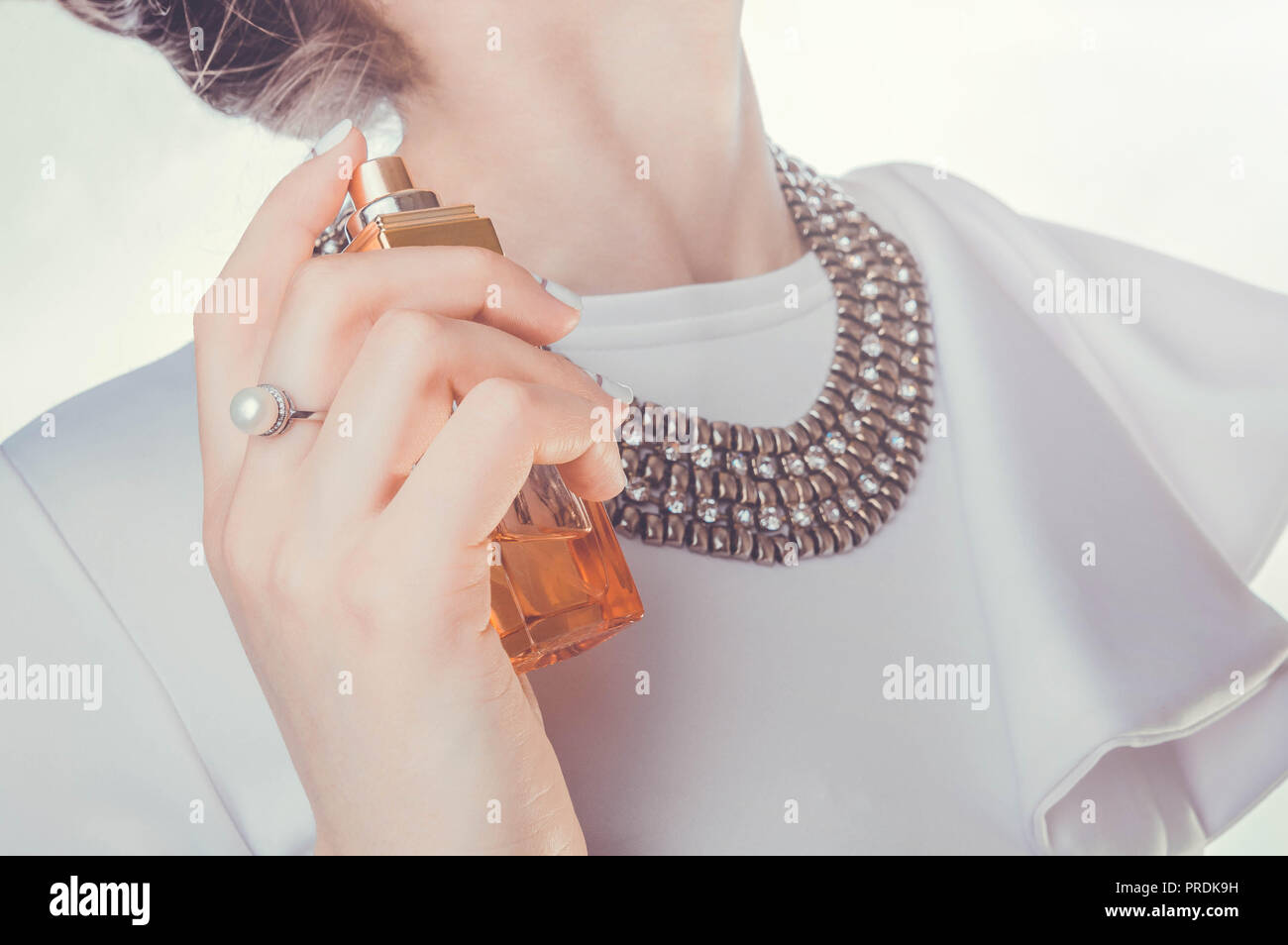 Woman in white dress applying perfume on her neck Stock Photo - Alamy