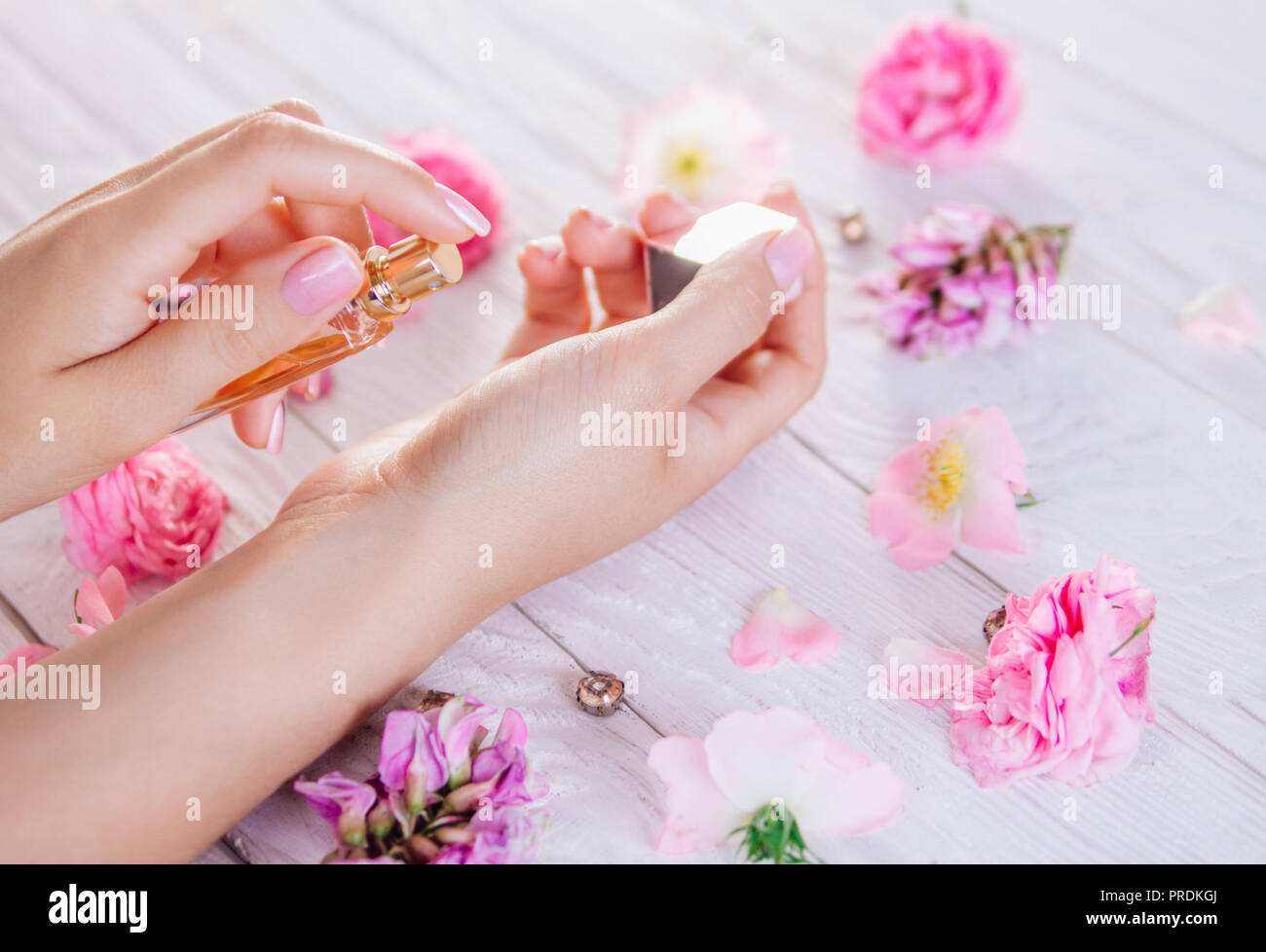 Woman applying perfume on her wrist surrounded with flowers Stock Photo ...