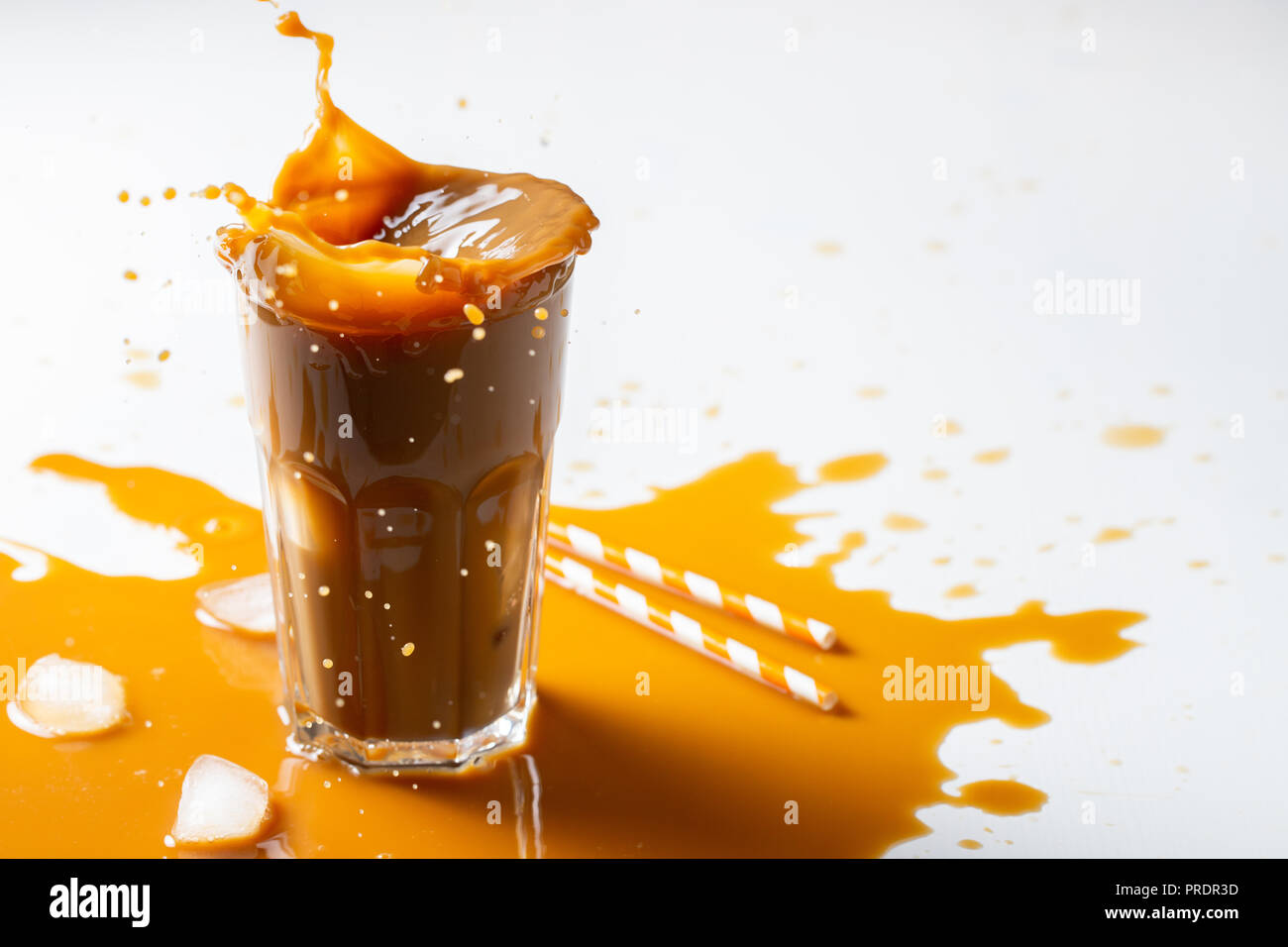 Iced latte coffee splash with ice cubes and roasted beans on a white ...