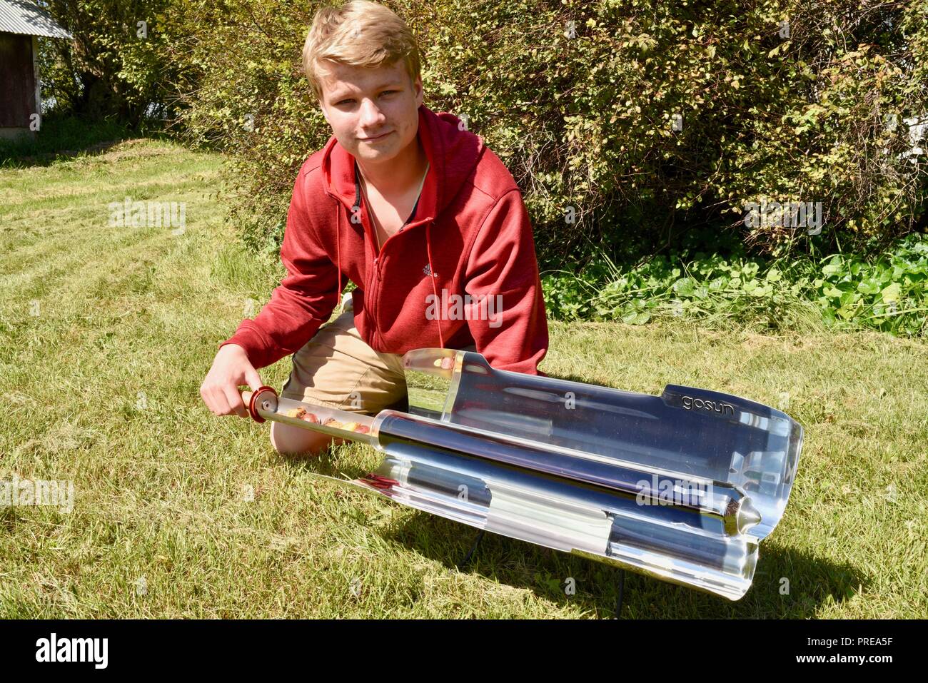 Teenage male boy cooking a meal in a GoSun Sport solar sun oven set ...