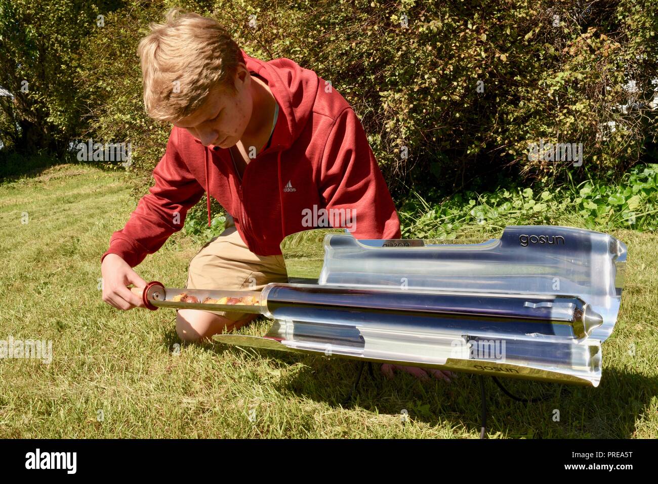 Teenage male boy cooking a meal in a GoSun Sport solar sun oven set ...