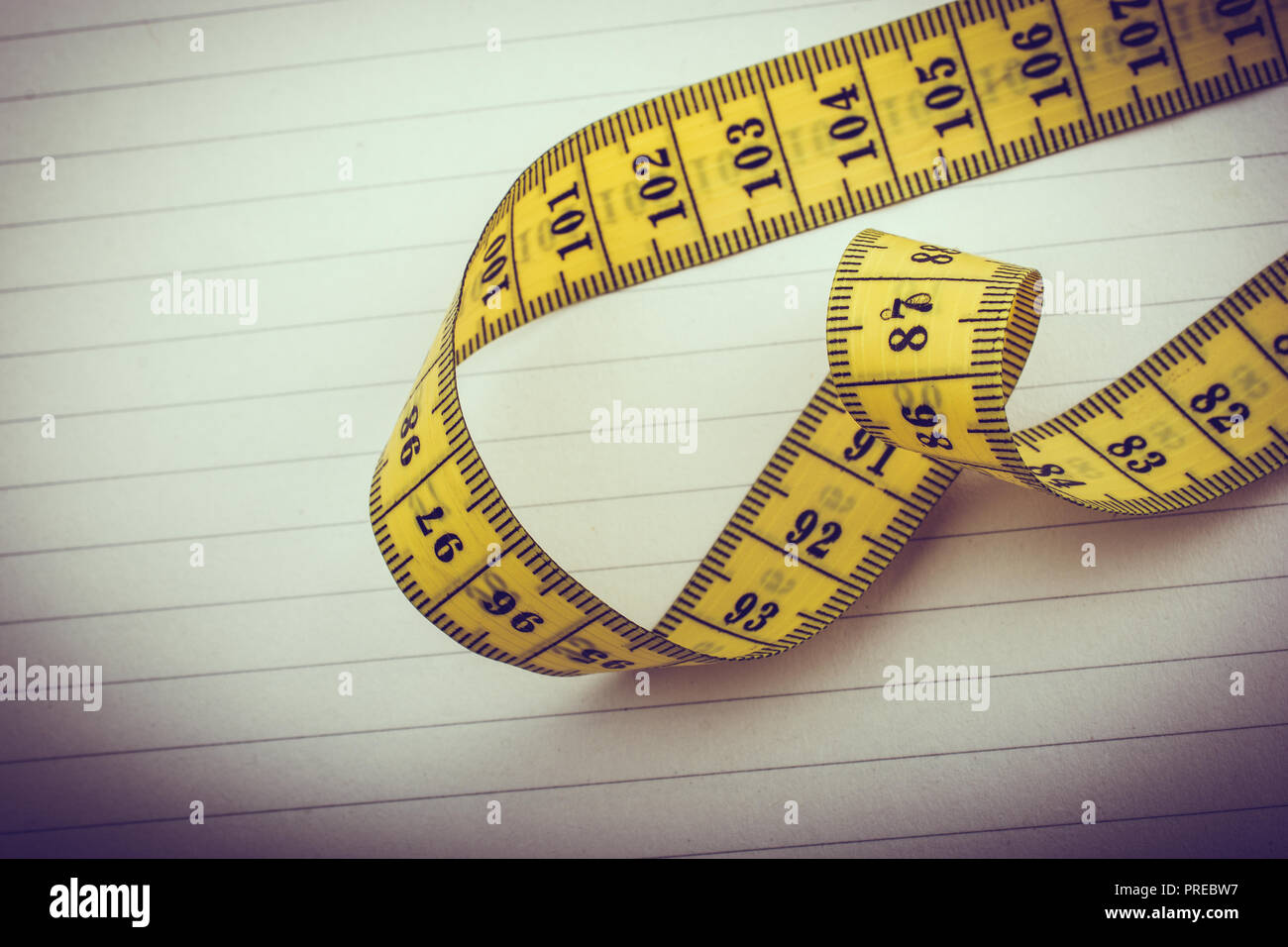 Yellow color measuring tape on lined paper Stock Photo - Alamy