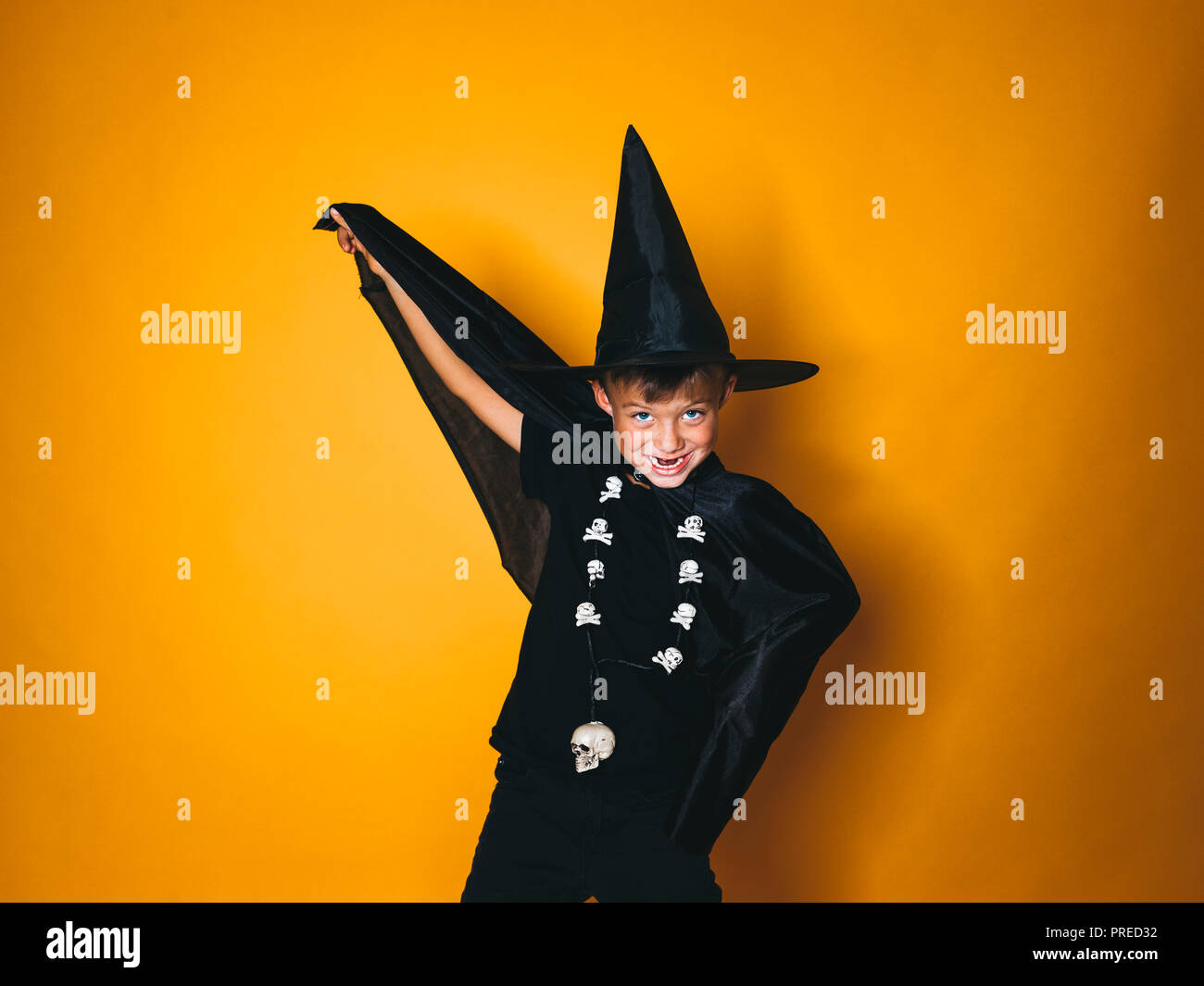 boy is dressed as a halloween witcher in front of orange background ...