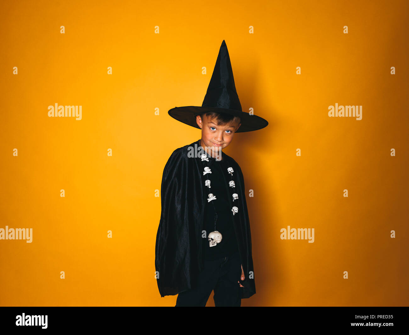 boy is dressed as a halloween witcher in front of orange background ...