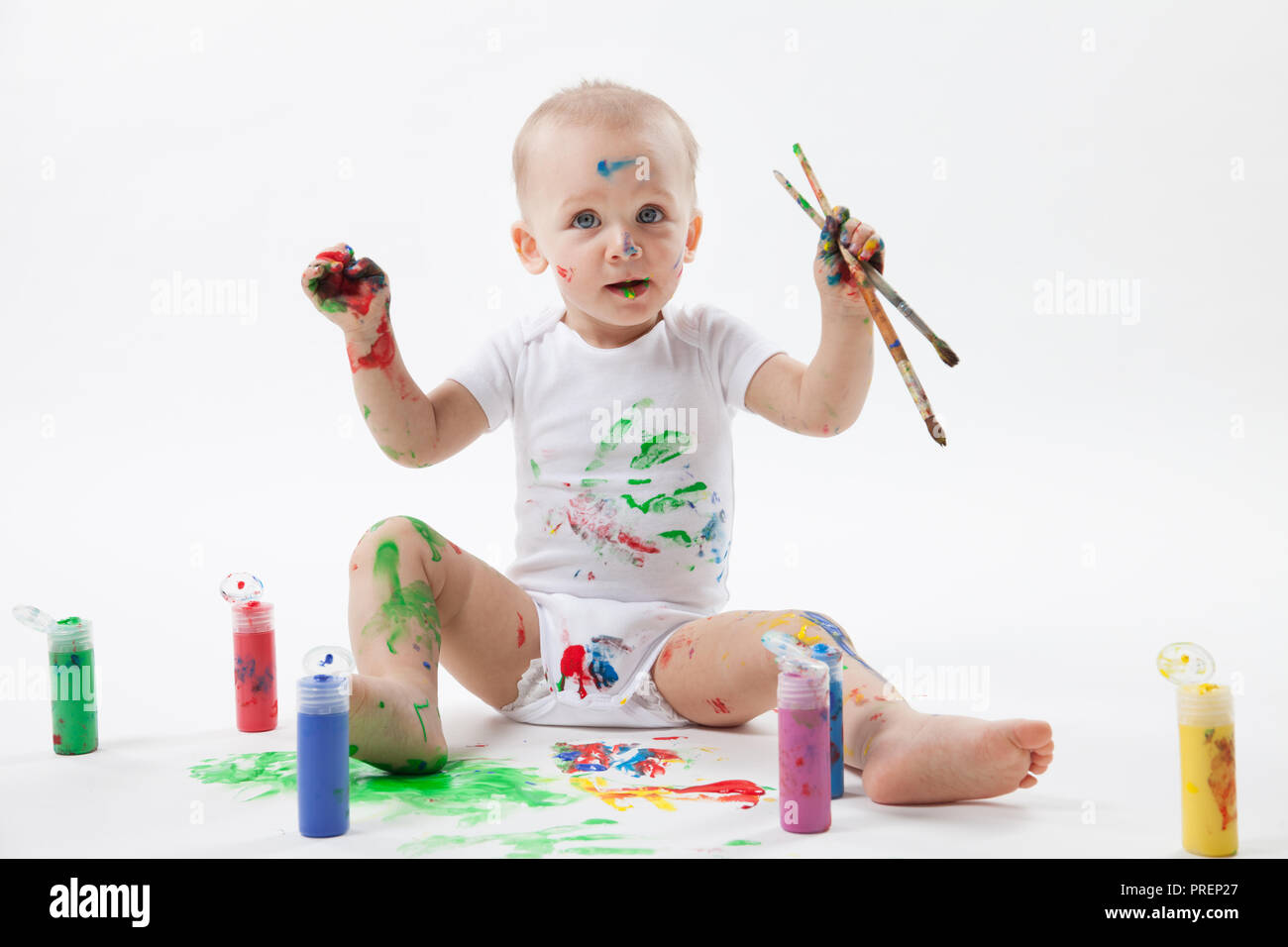 Cute little baby painting with paintbrush and colorful paints on white ...