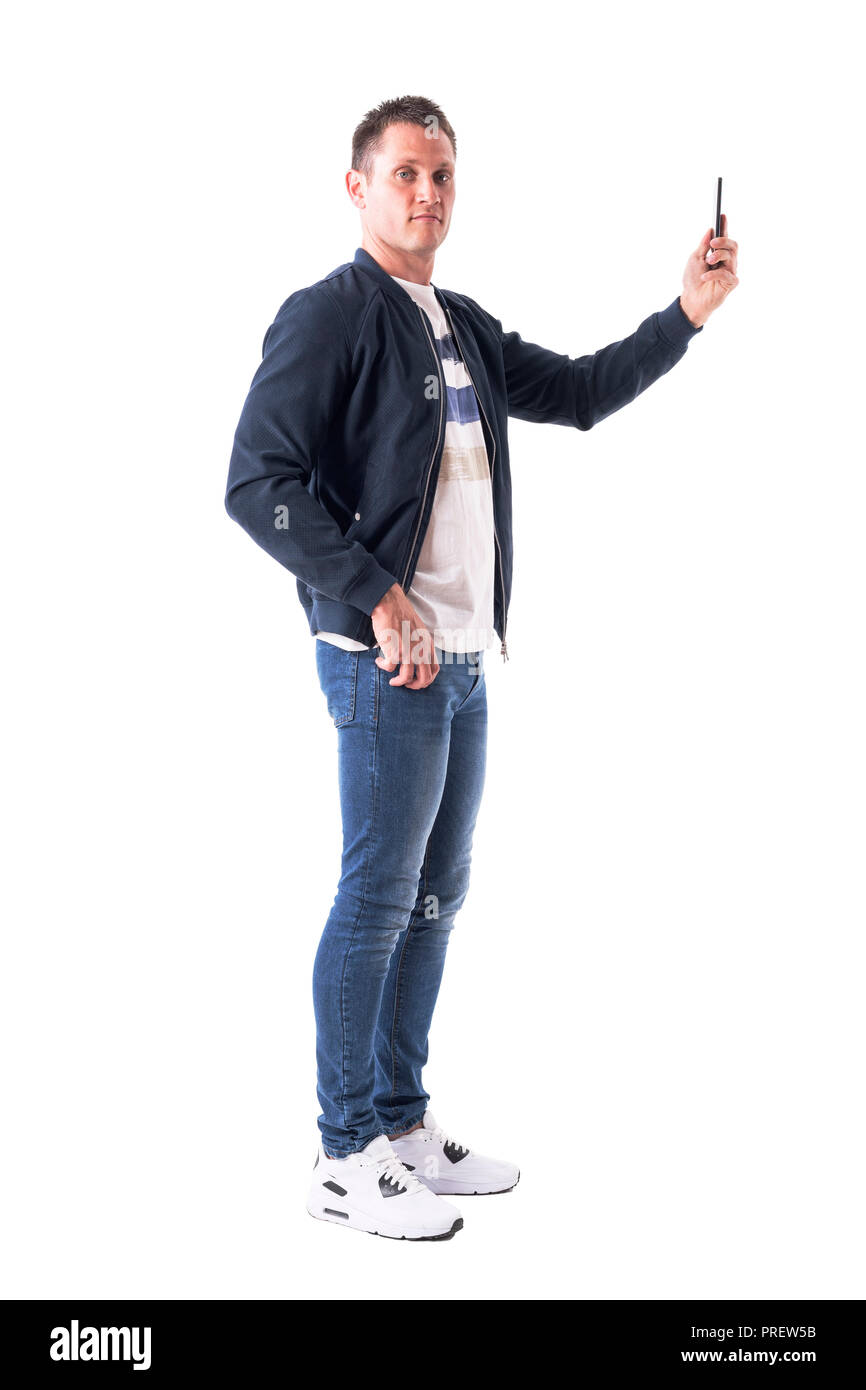 Side view of young man taking photos with mobile phone and looking at ...