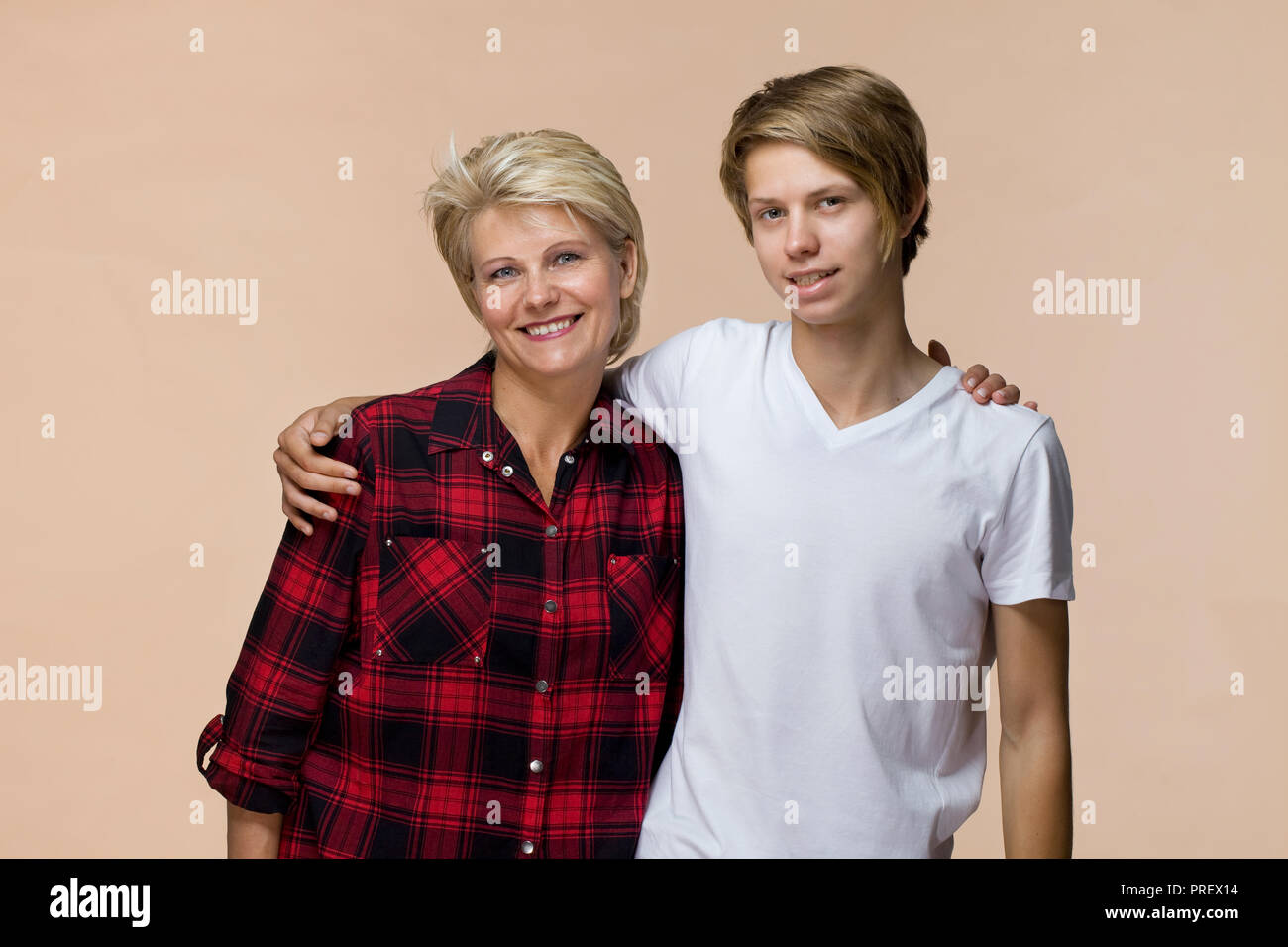 Happy family, hugging mother and son smiling portrait against brown ...
