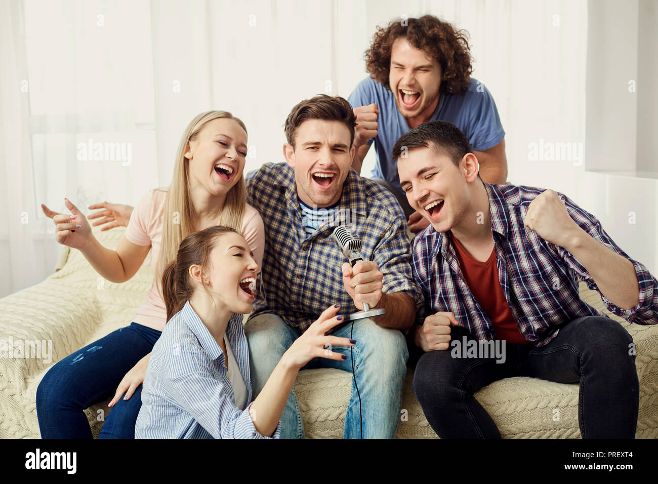 A group of friends with a microphone are singing fun songs indoo Stock ...