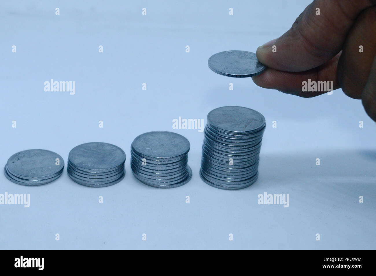 Putting a coin over a stack of coins. Isolated on white background ...
