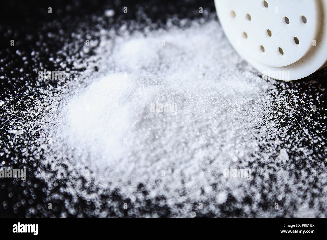 Slides of small crystals of salt are scattered on a black table Stock ...