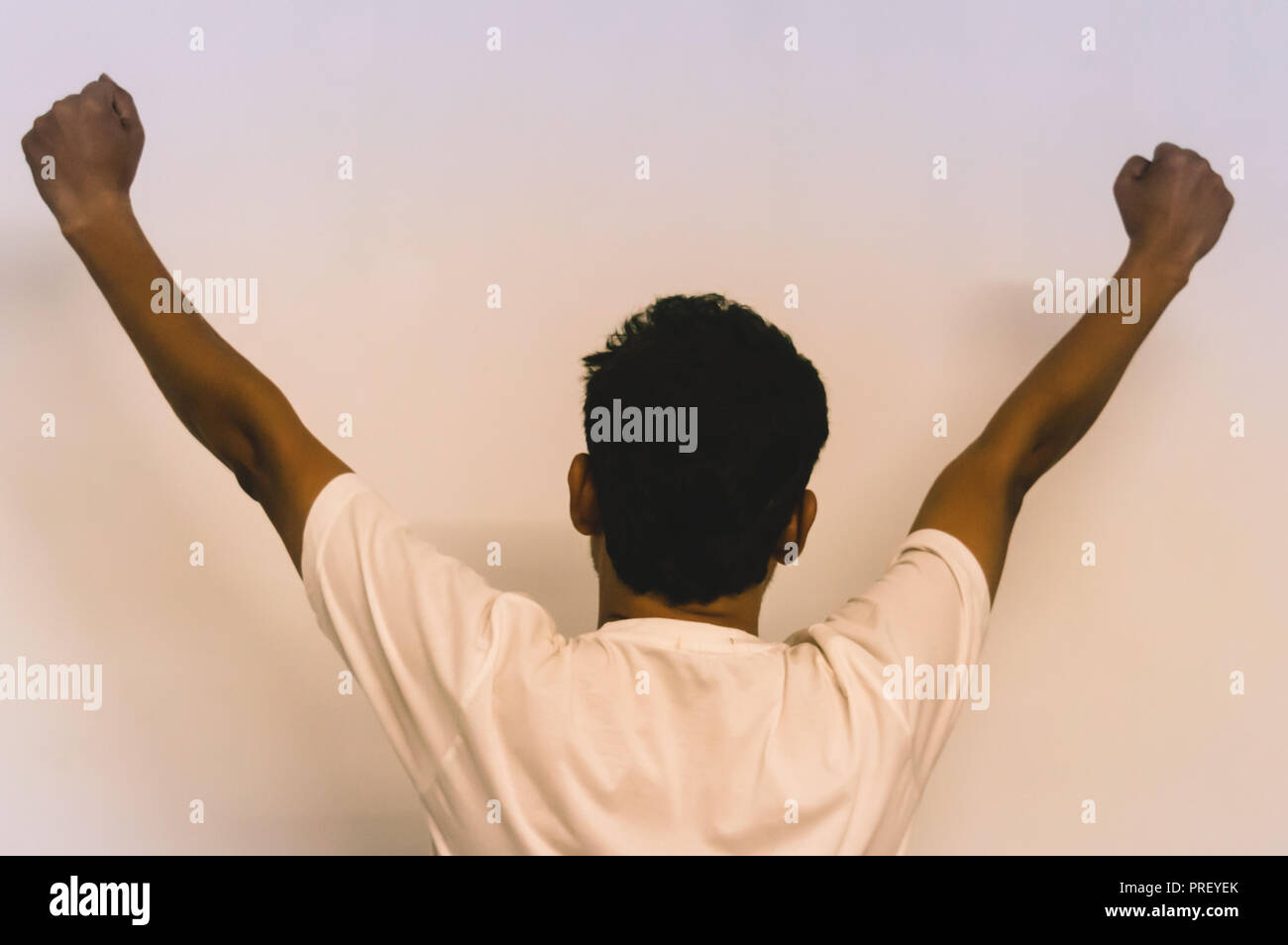 Studio shot of modern hipster young man with hands up, back view ...